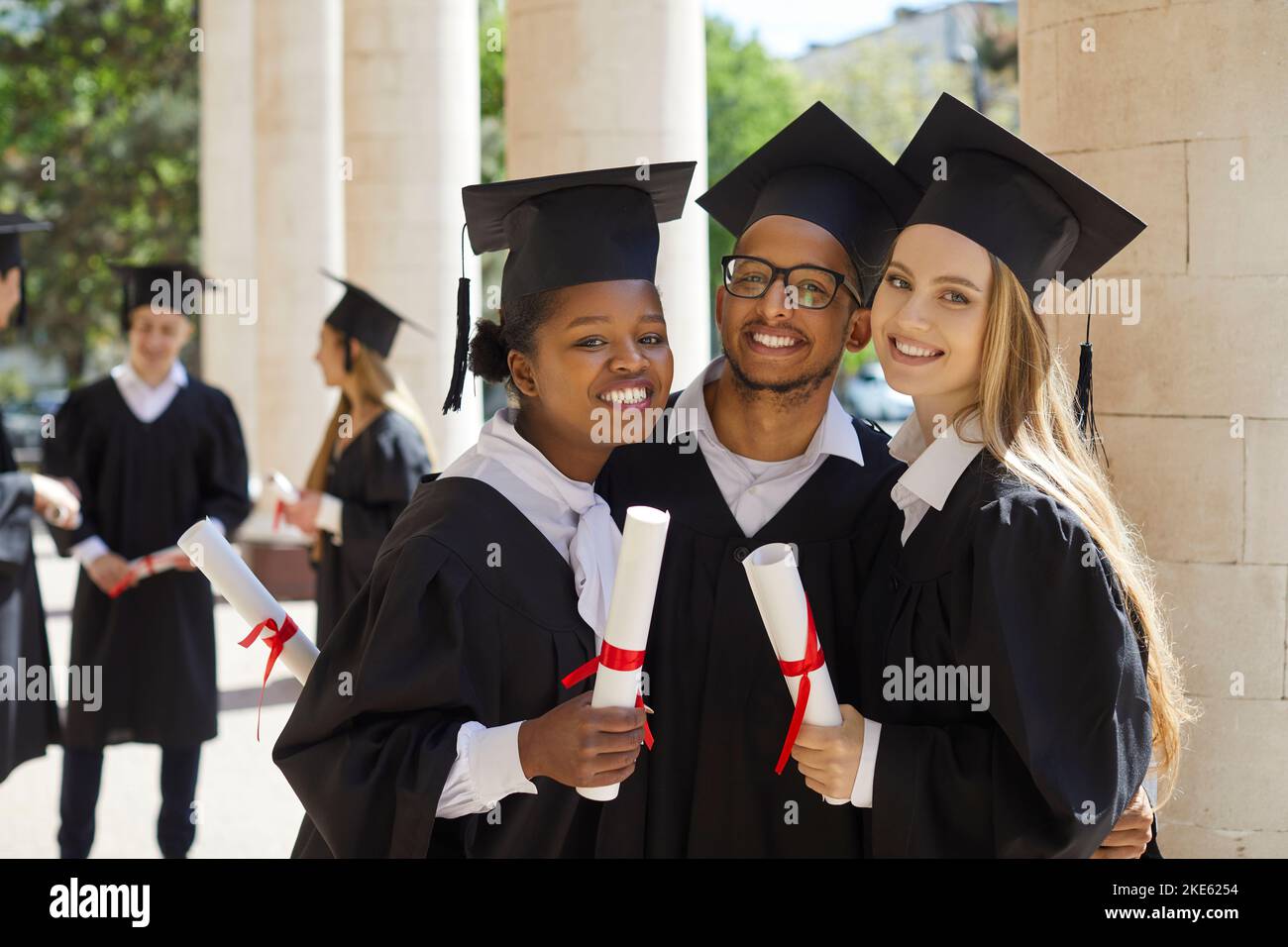 Portrait of three university graduate friends with diplomas in their ...