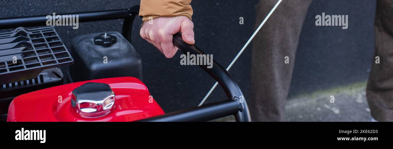 partial view of man starting power generator outdoors during ...
