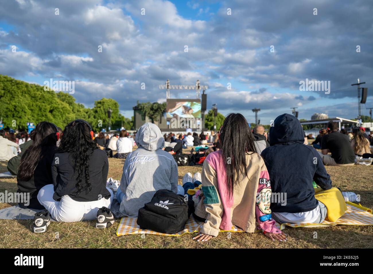 People sitting on grass viewing open air outdoor cinema in Hyde Park ...