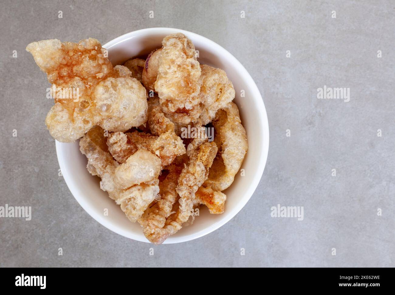 Perfectly crisp, pork rind or crackling in white bowl with copy space ...