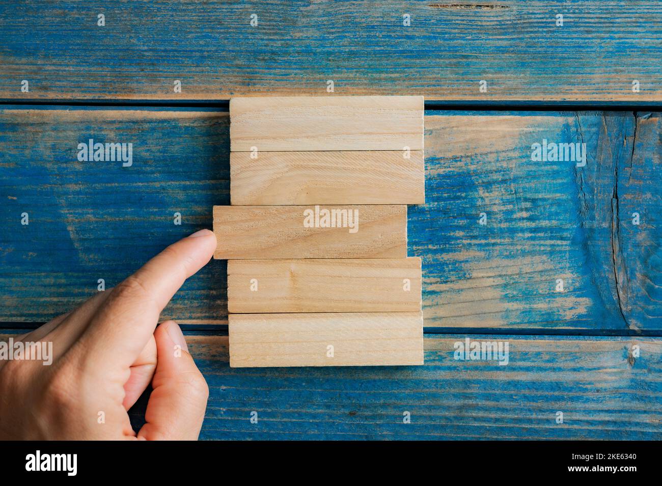 Male finger pushing a simple blank wooden peg into a stack of them in a ...