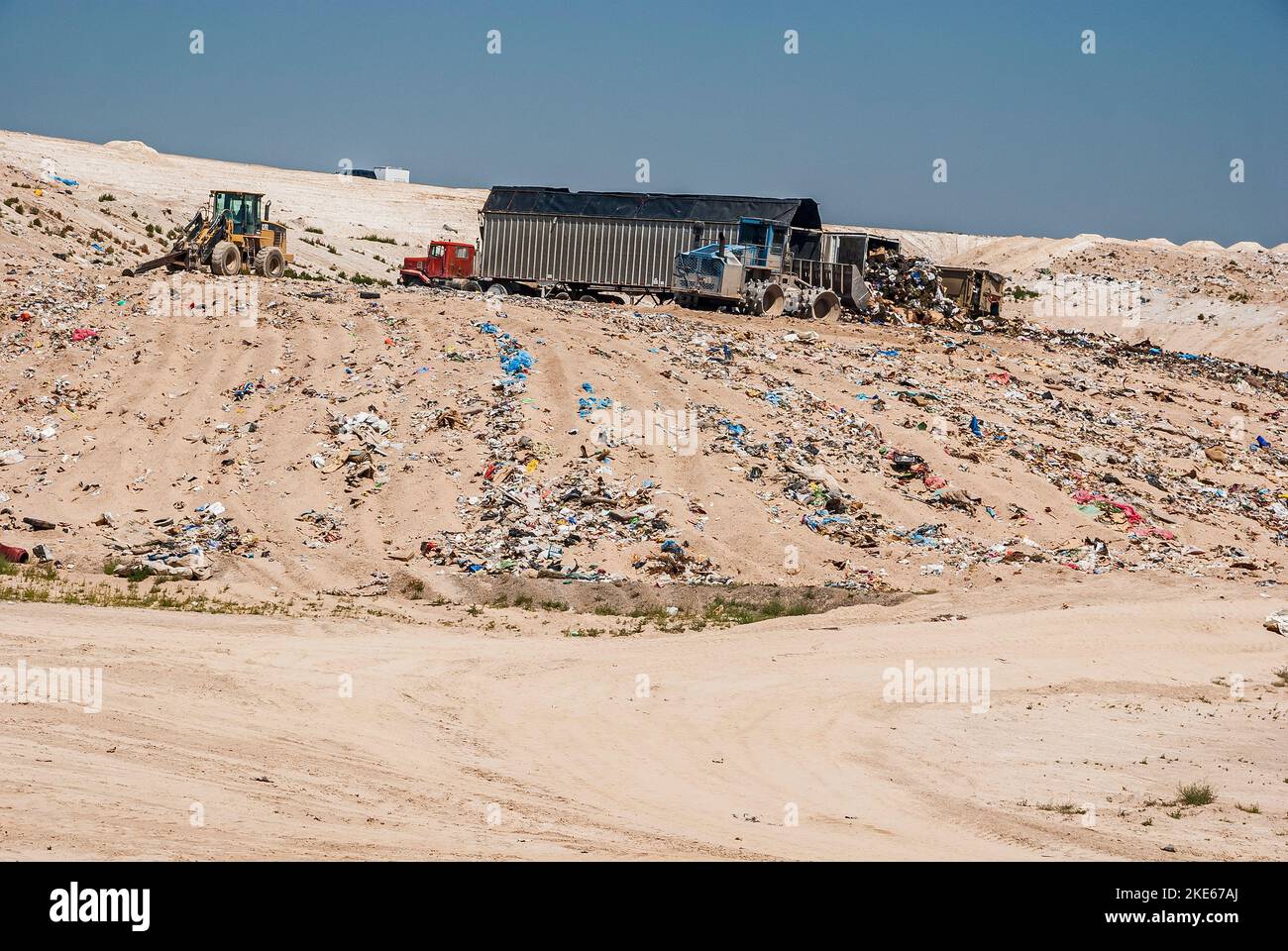 A tractor-trailer semi and two soil compactors on flat land in an ...