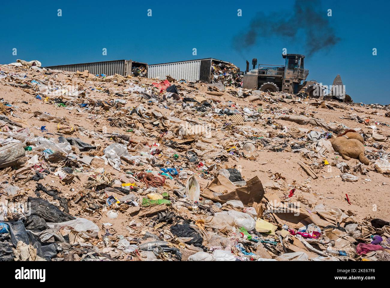 A soil compactor emitting black diesel smoke, and two trailers dumping ...