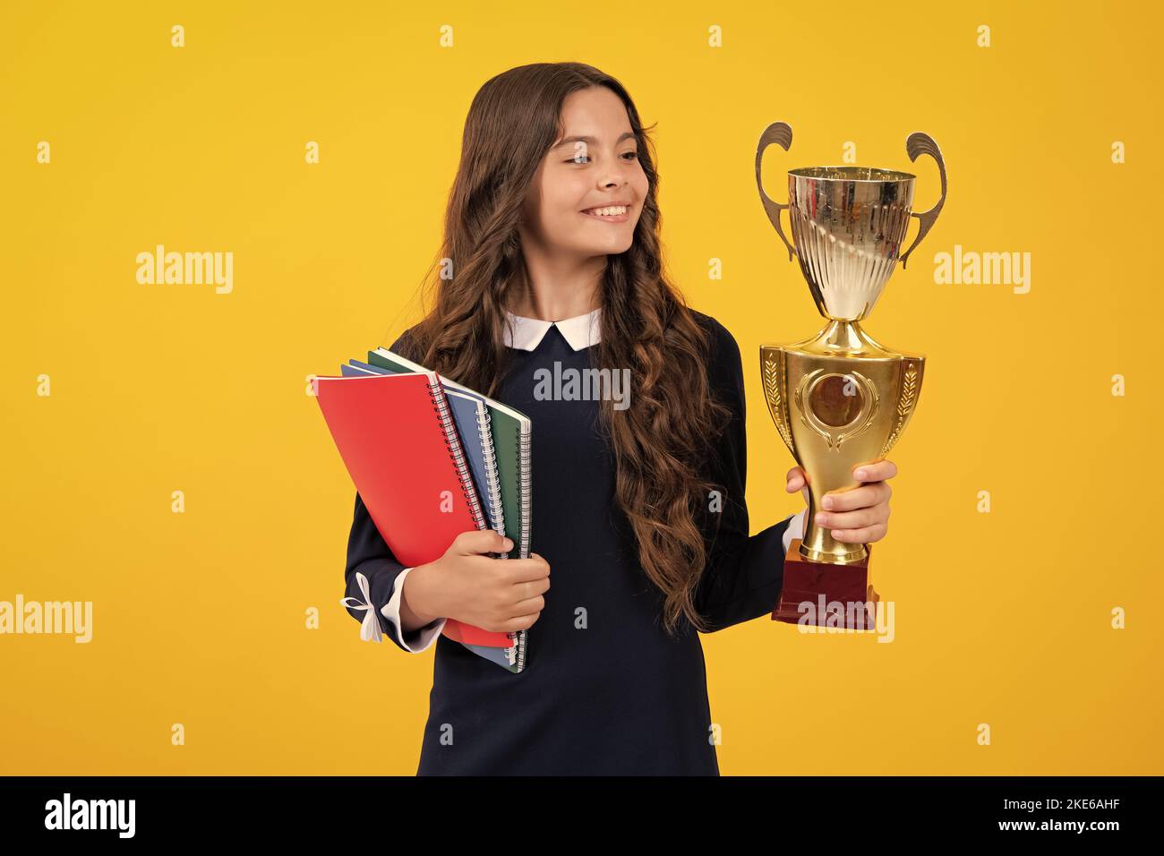 Schoolgirl in school uniform celebrating victory with trophy. Teen ...