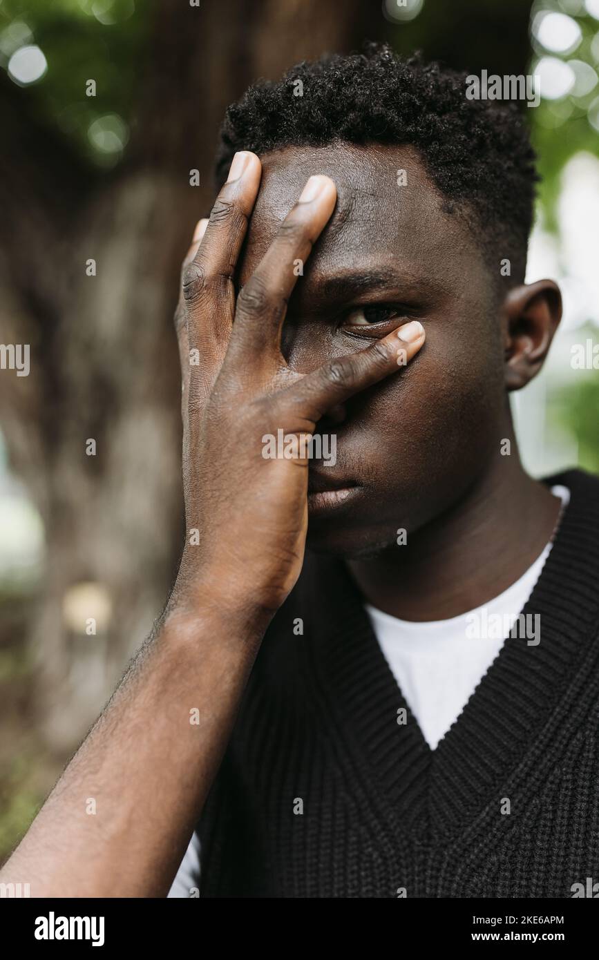 Bored and sad young 20s African man wear casual streetwear in park ...
