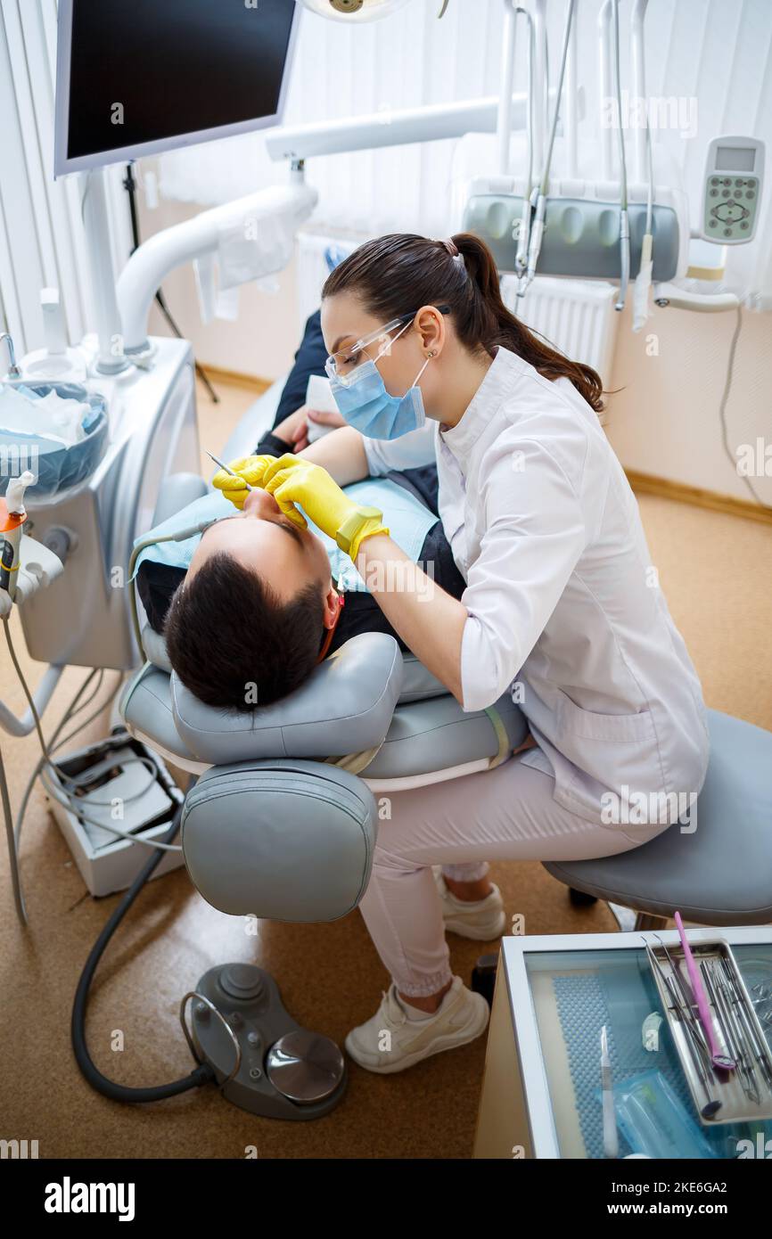 The dentist in the office treats the teeth of the patient who is in the ...