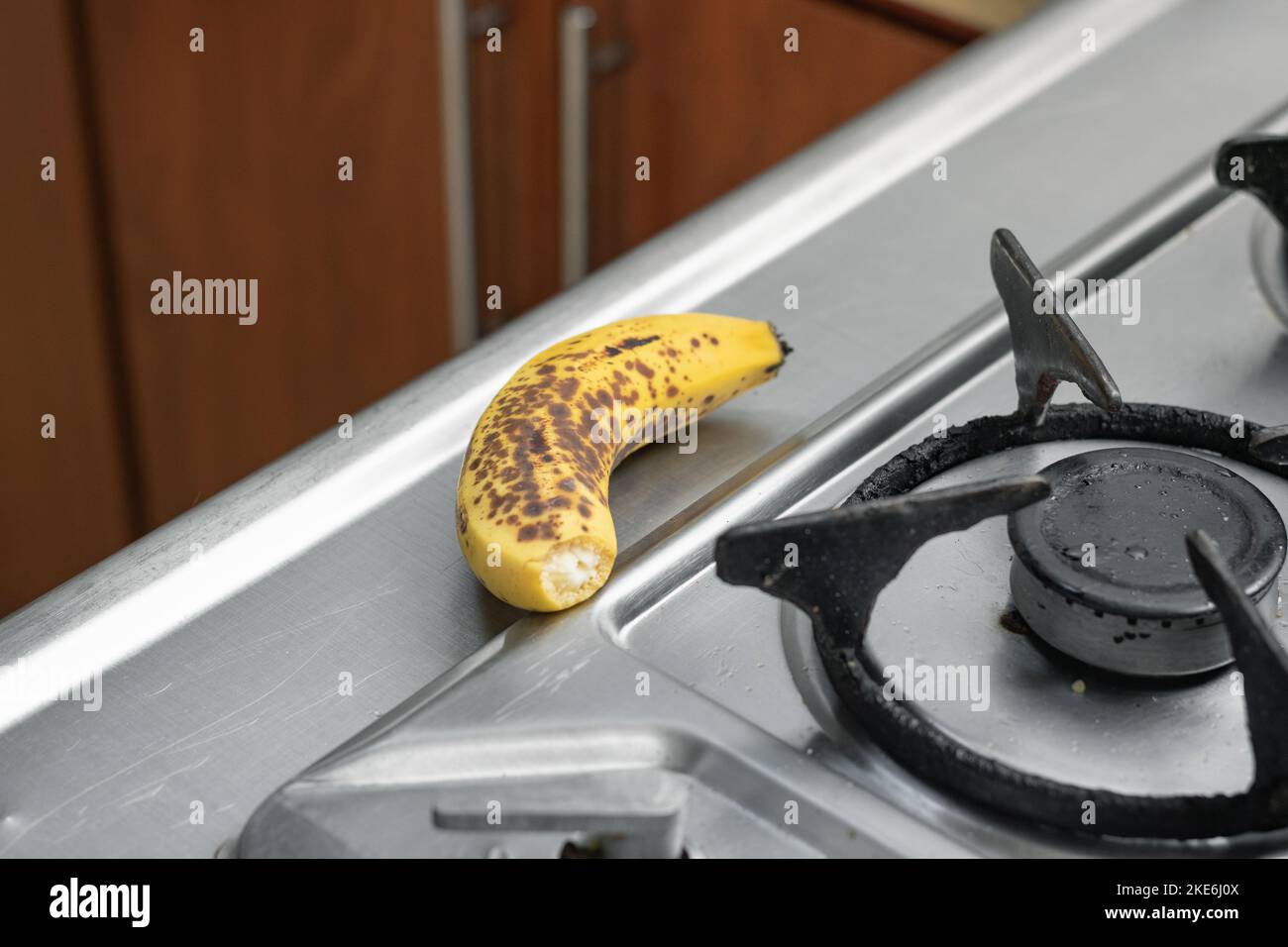 ripe banana placed next to the gas stove, in a kitchen with wooden ...