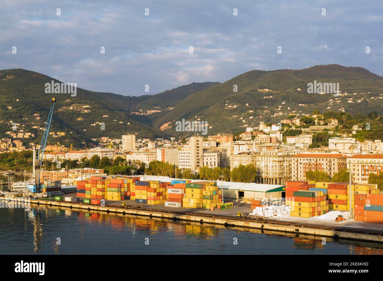 Stacked shipping containers and blue gantry crane on dock in commercial ...