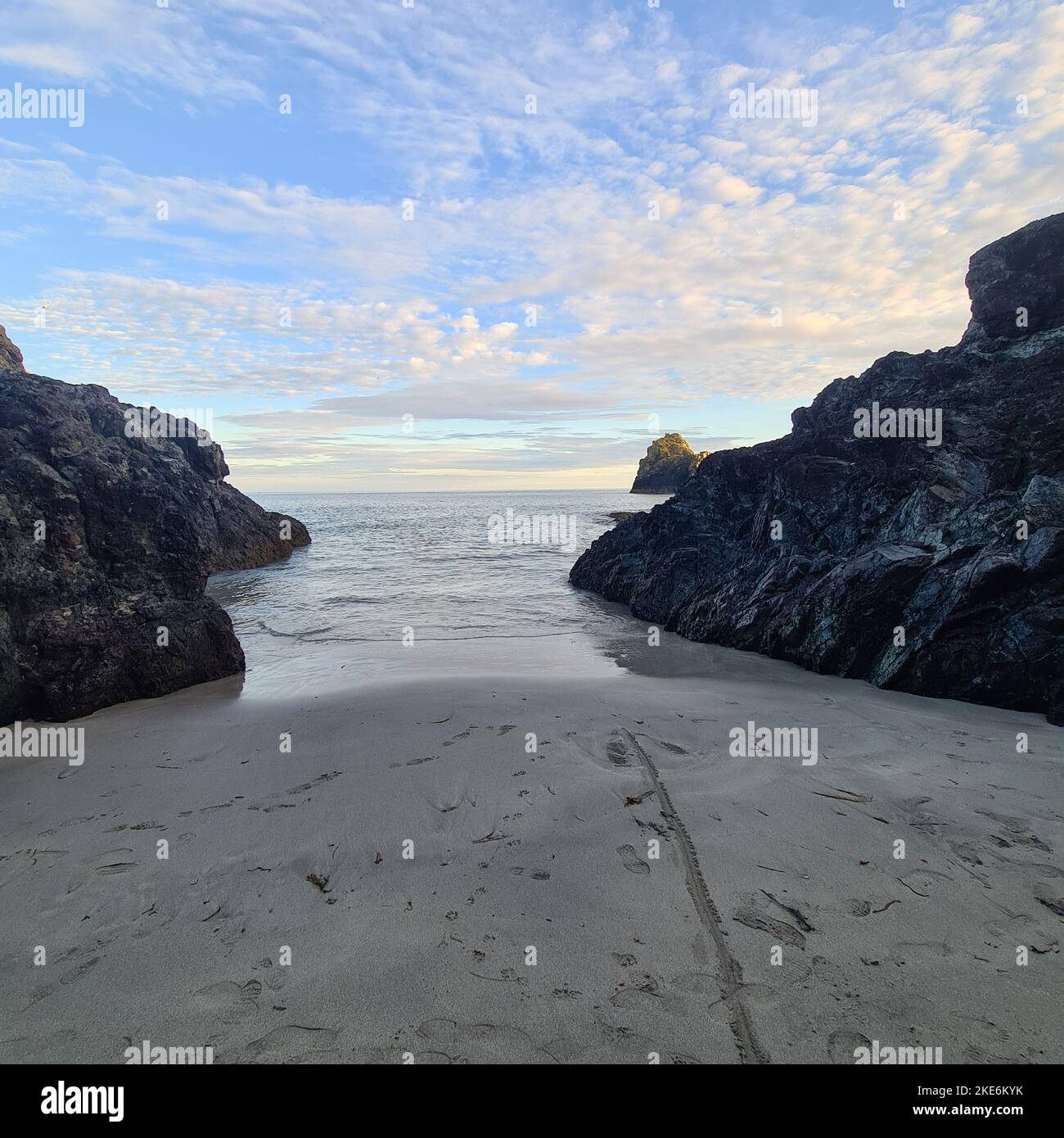A Seascape between huge rocks in a sandy beach at sunset Stock Photo ...