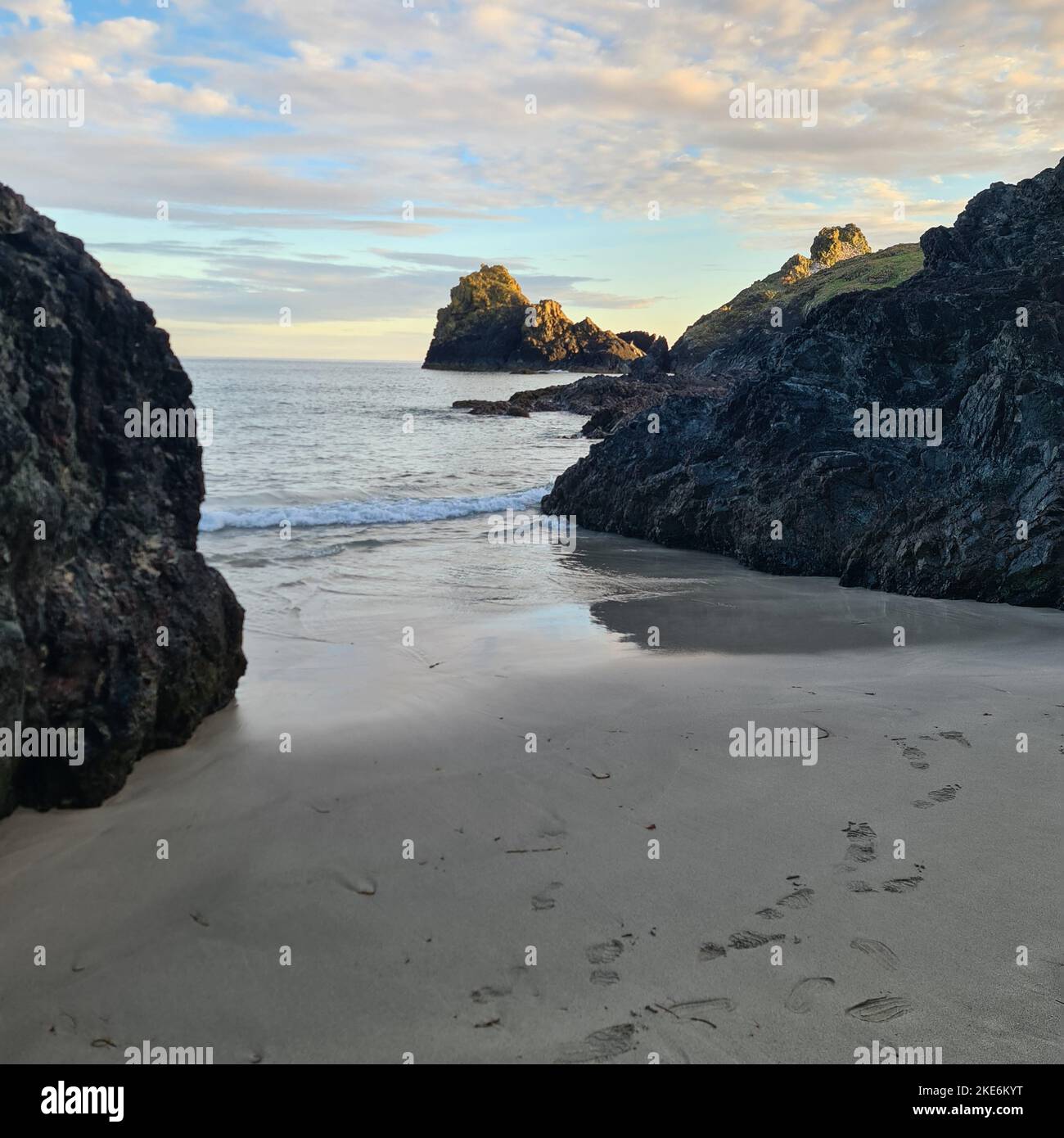 A Seascape between huge rocks in a sandy beach at sunset Stock Photo ...