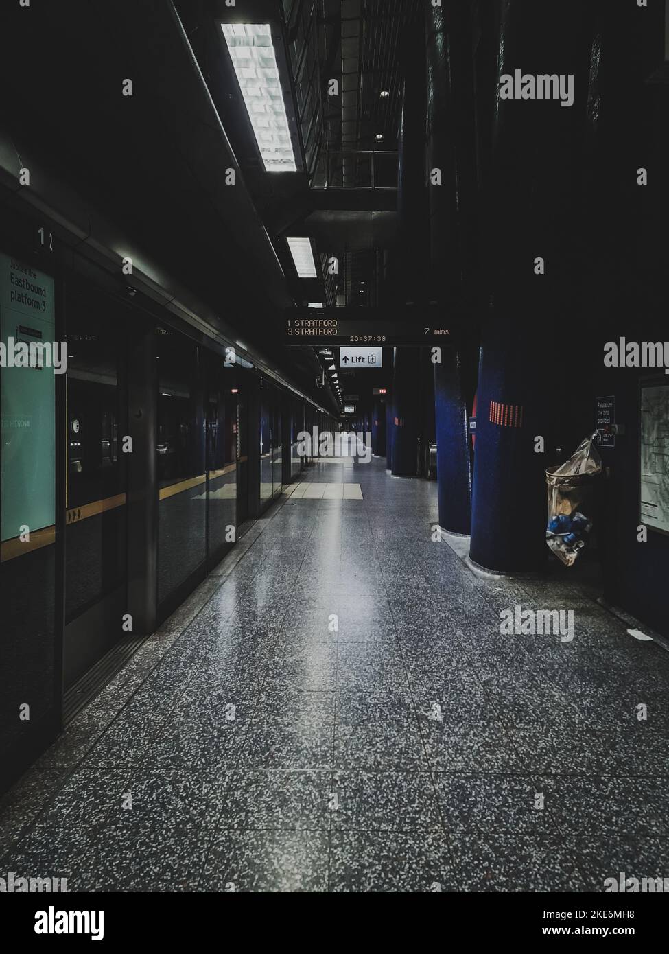 The platform edge doors and signs at a dark underground station in the ...