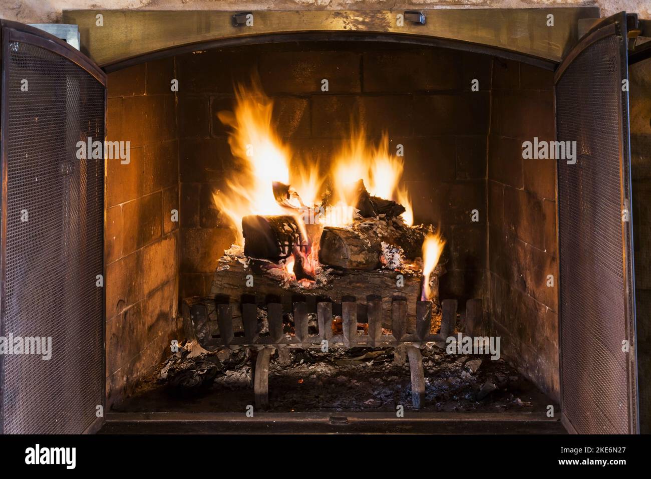 Lit wood burning fireplace in living room inside old renovated circa ...