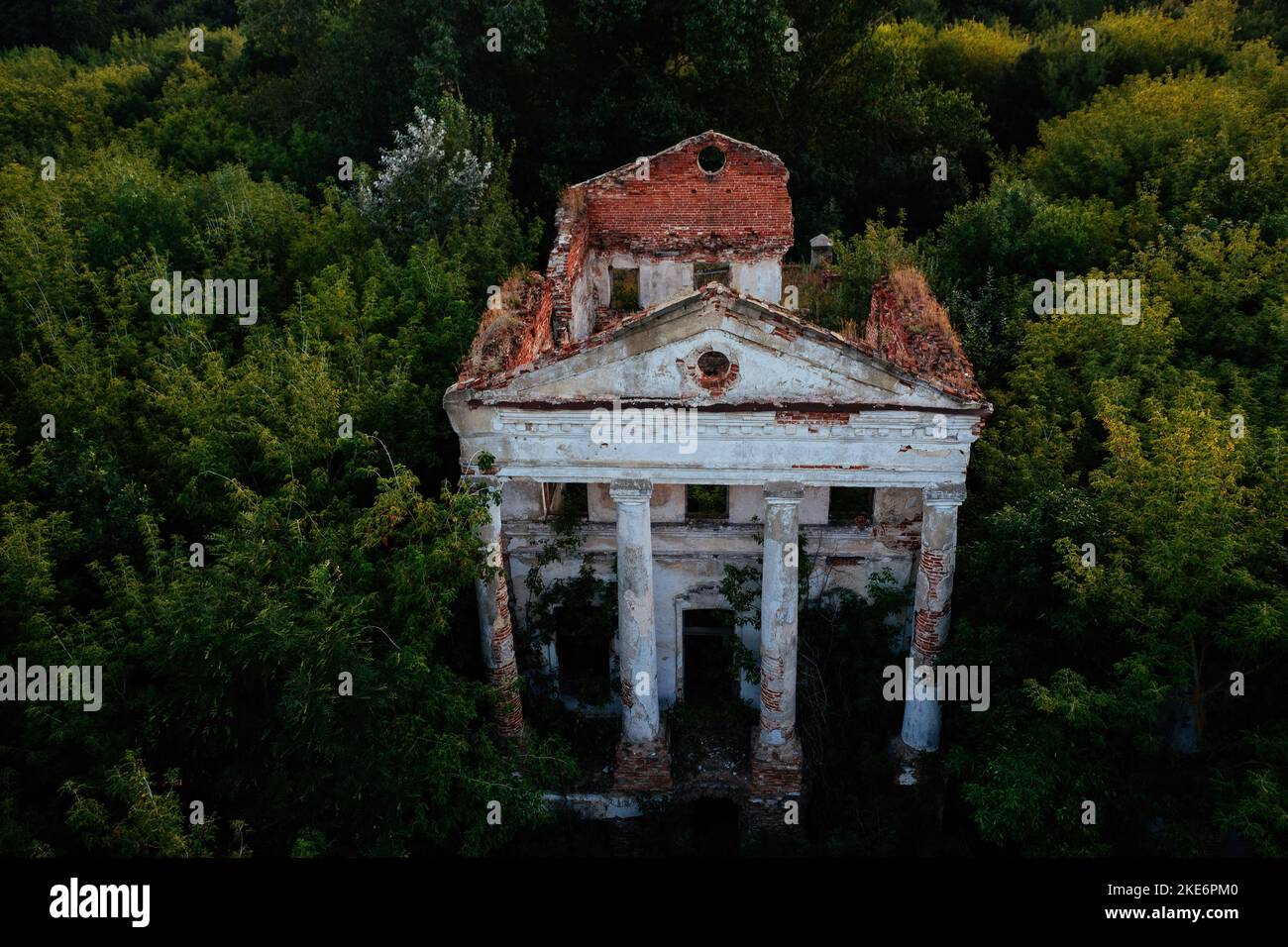 Old ruins of abandoned mansion overgrown by plants, aerial view. Former ...