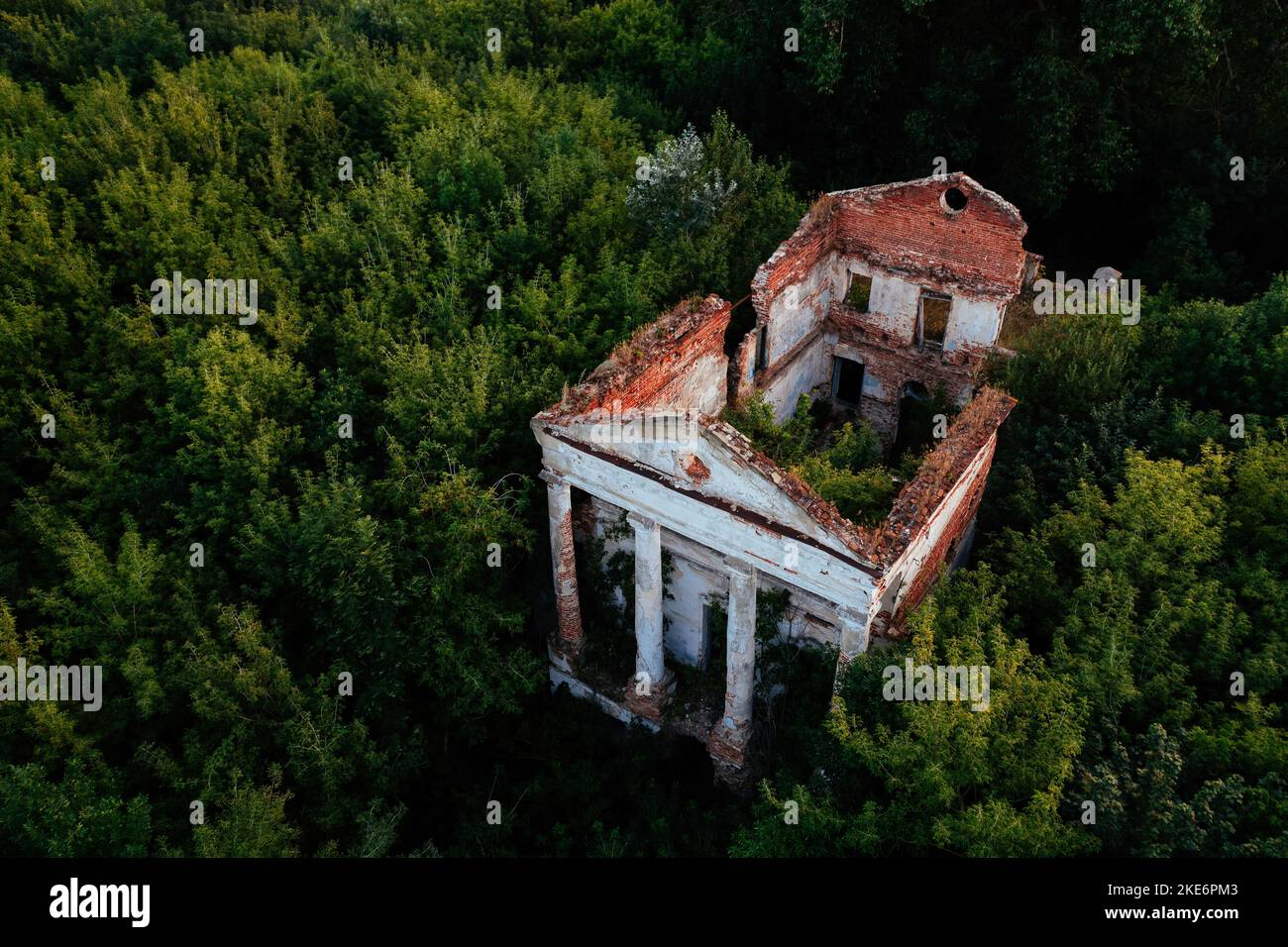 Old ruins of abandoned mansion overgrown by plants, aerial view. Former ...