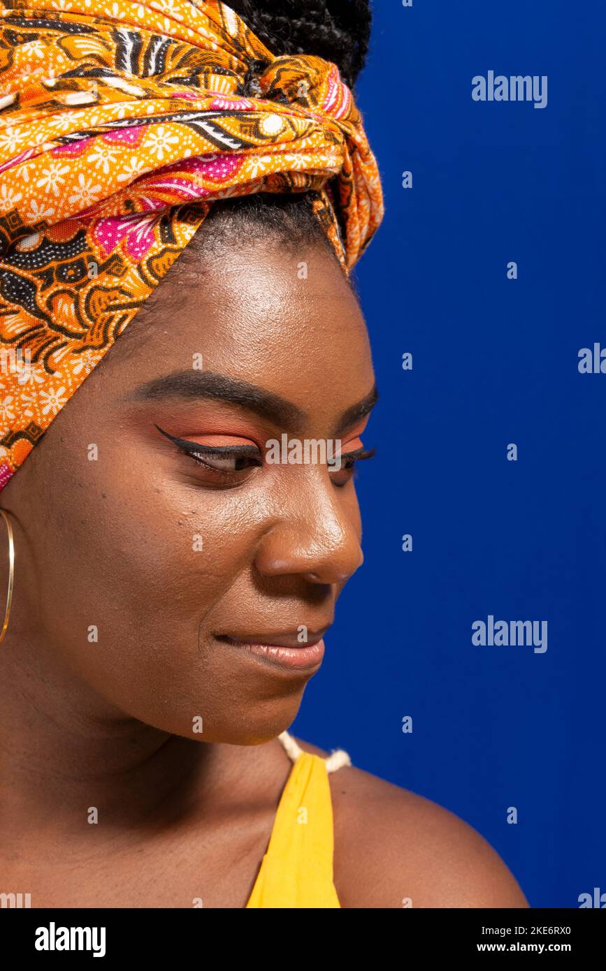 Close-up portrait of an Afro-Brazilian woman against blue background ...