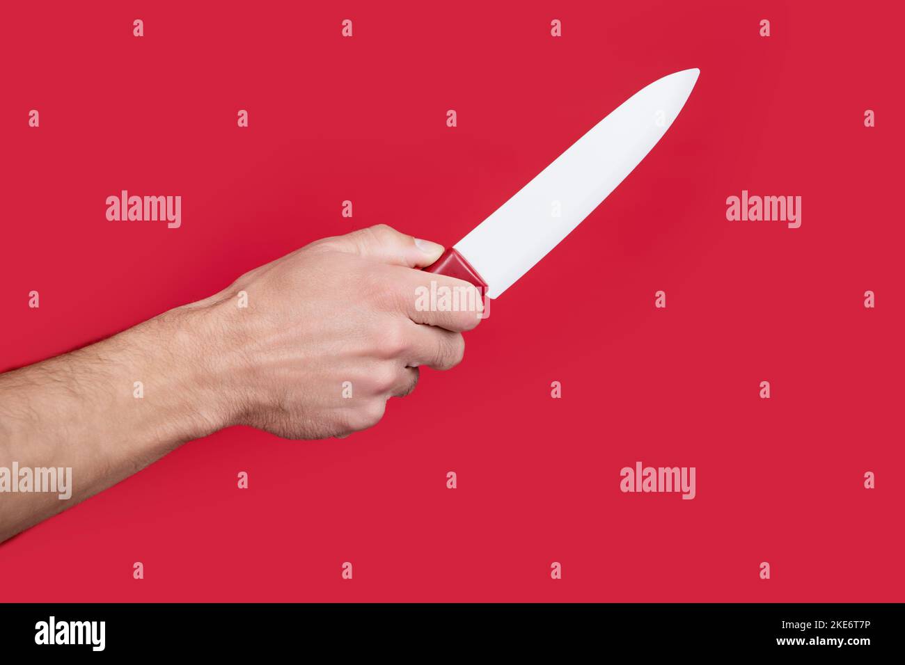 sharp kitchen knife in male hand on red background Stock Photo - Alamy