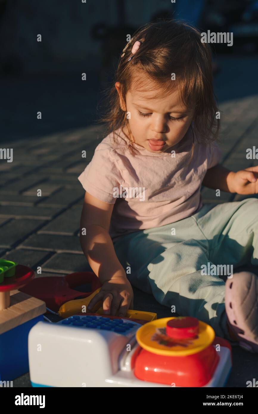 Happy baby boy playing with colorful plastic toys on playground for ...