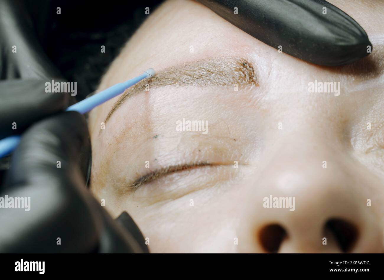 Close-up. The beautician cleans the eyebrows of a woman after the ...