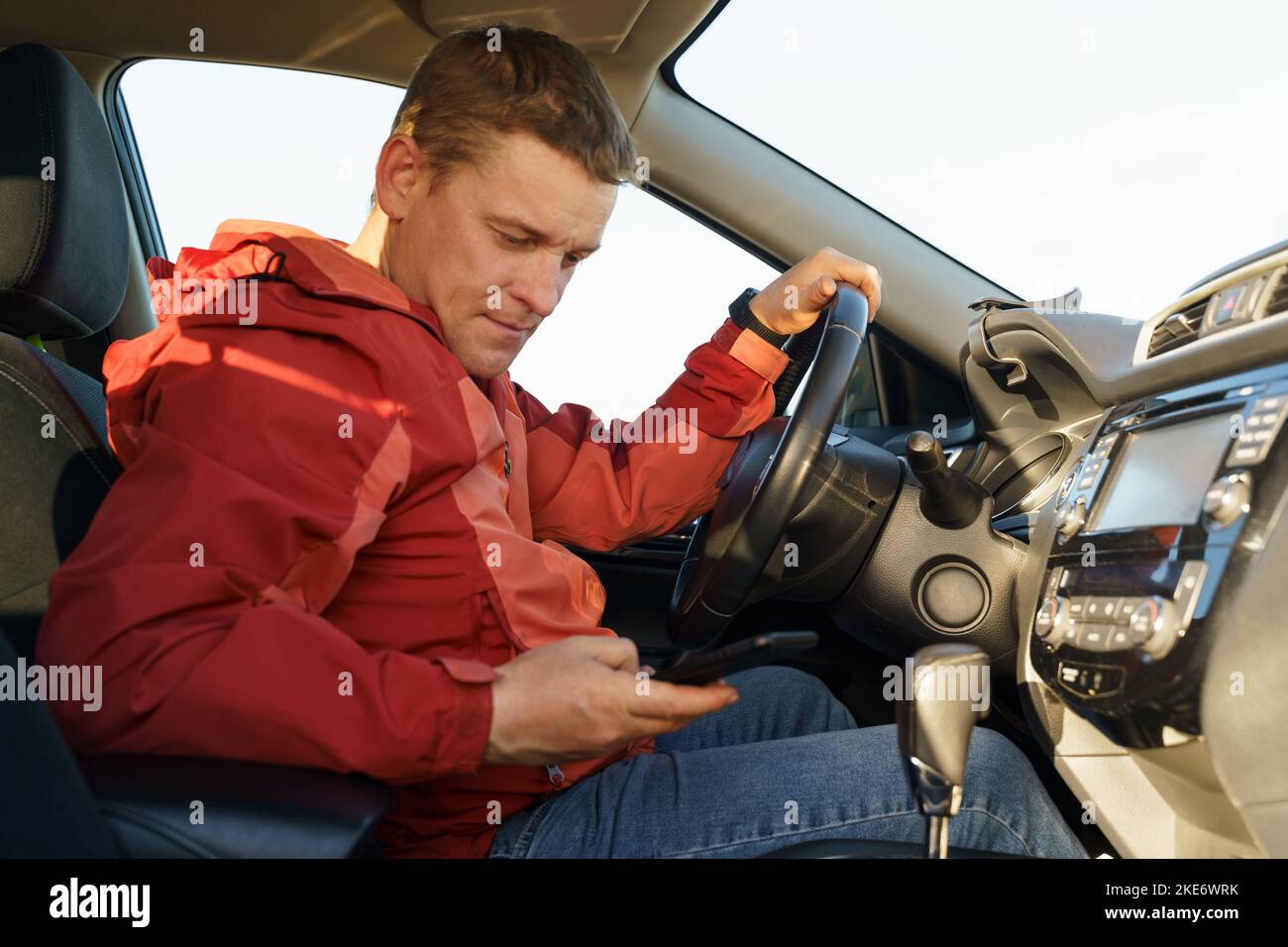 Driver man looks at the phone while the car is moving. Road safety ...
