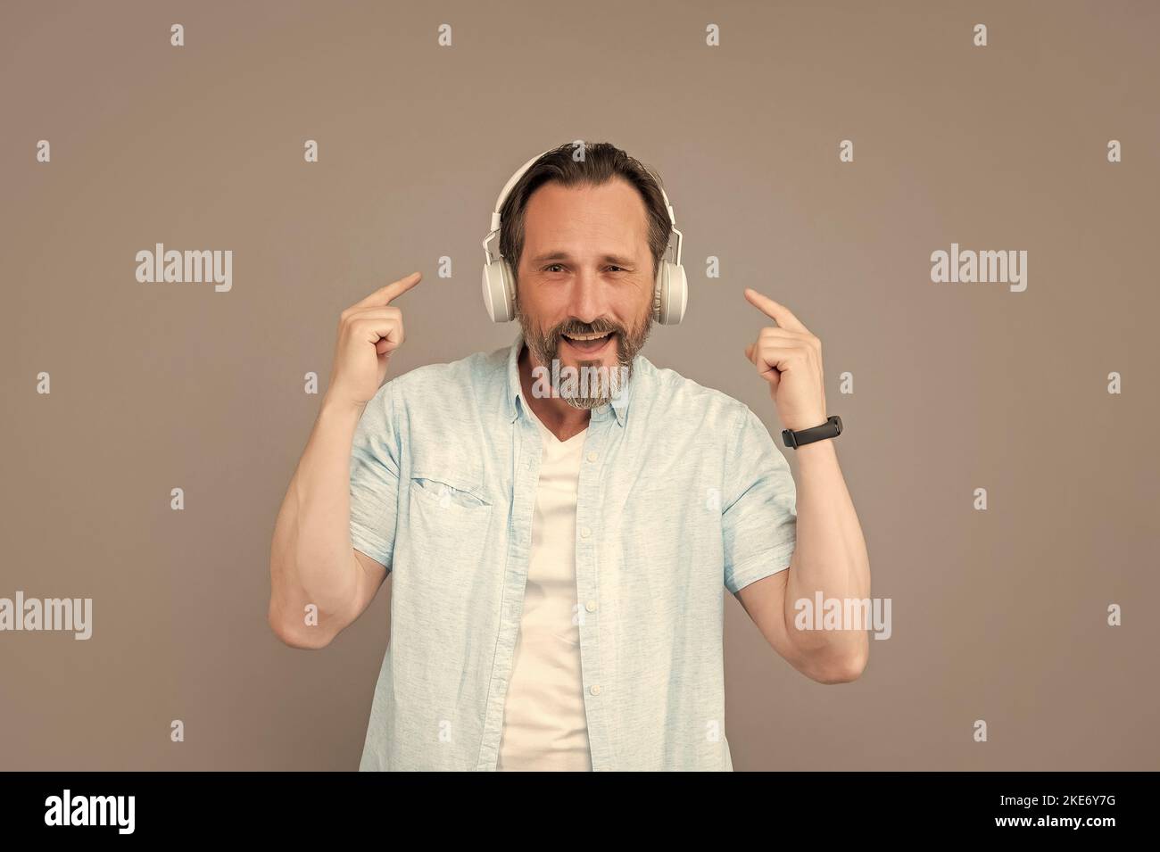 Headphones in, volume up. Happy old man point at headphones. Listening ...