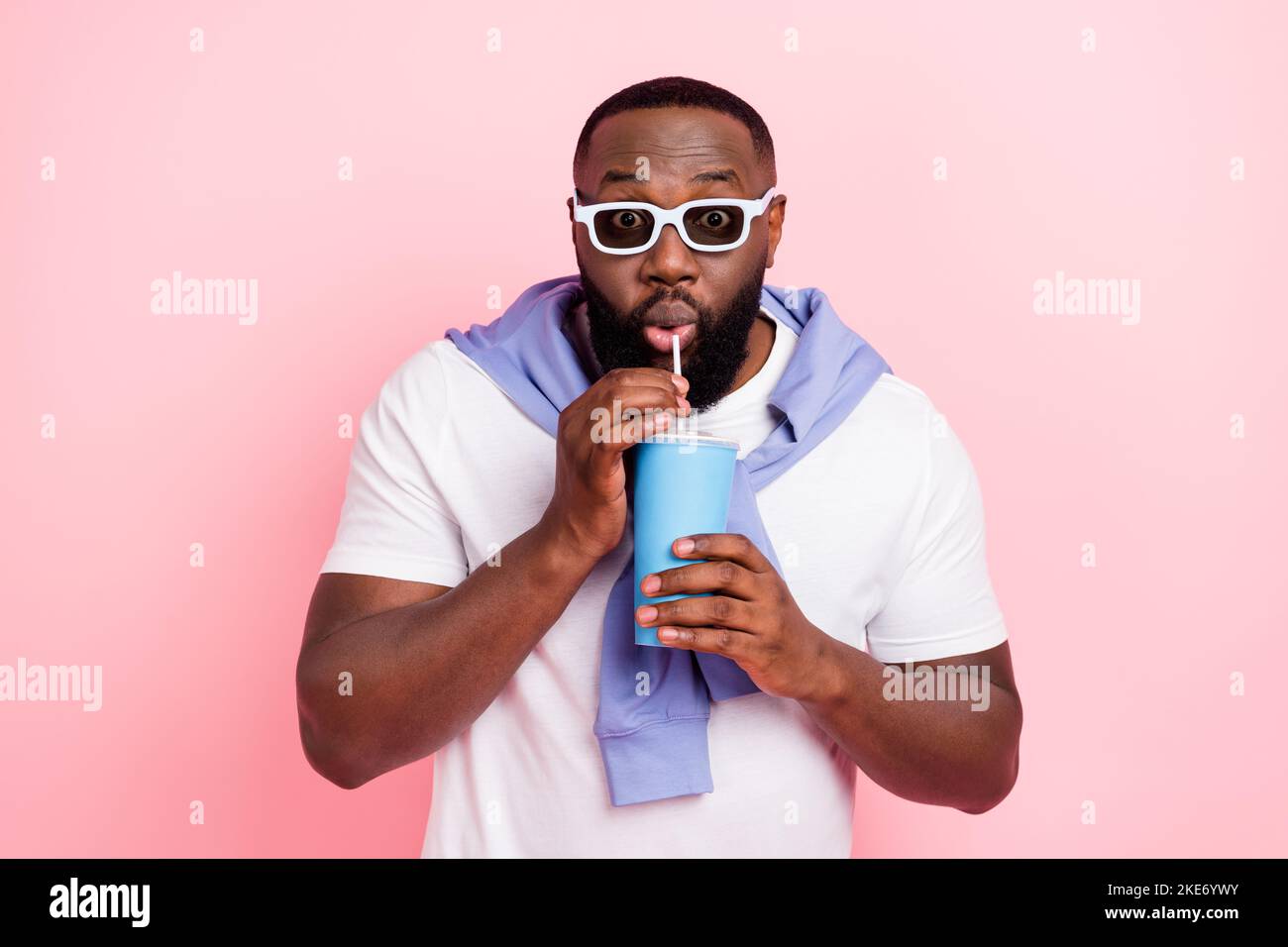 Photo of scared young man watching in stupor crazy horror movie sipping ...