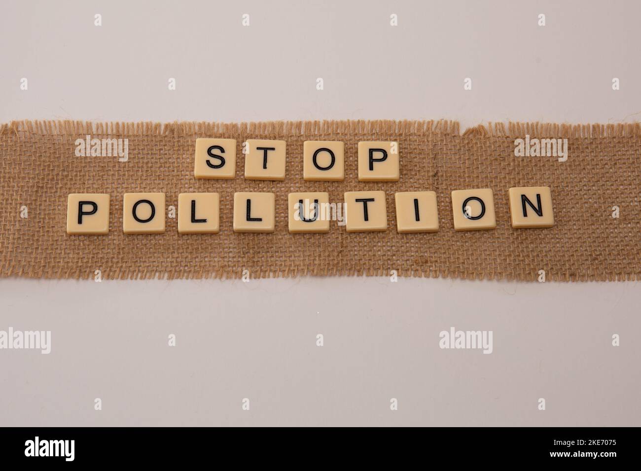 The letter tiles spelling stop pollution laying on jute ribbon isolated ...
