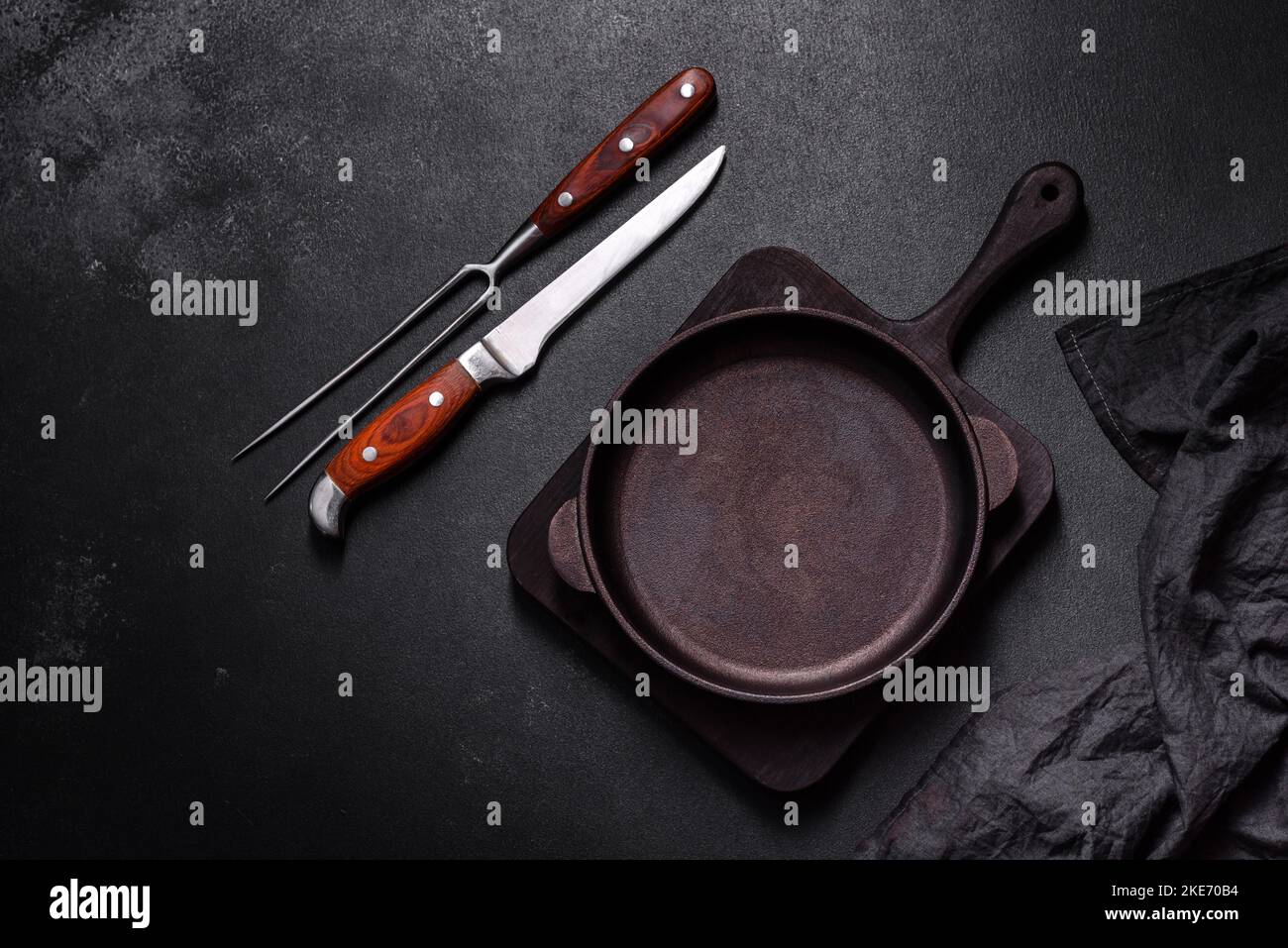 Brown iron empty pan with kitchen utensils on a dark concrete ...