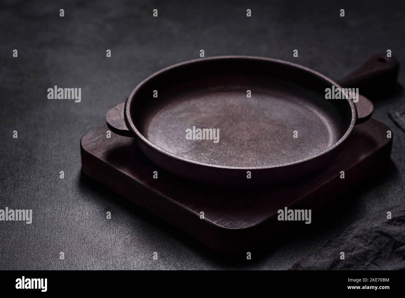 Brown iron empty pan with kitchen utensils on a dark concrete ...