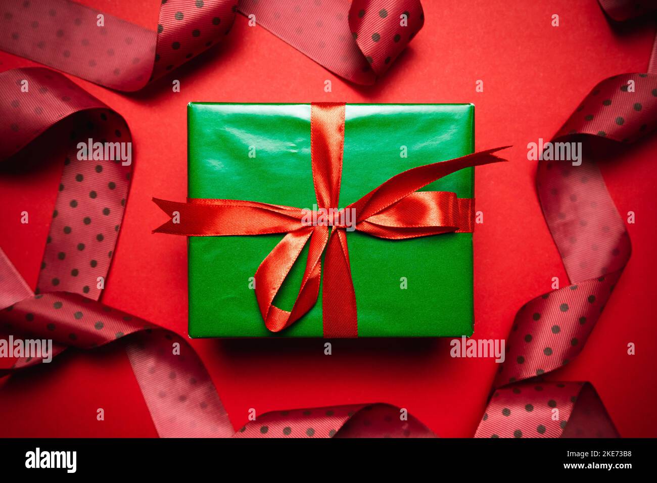 Green gift box with red ribbon flat lay. Concept of greeting card for ...