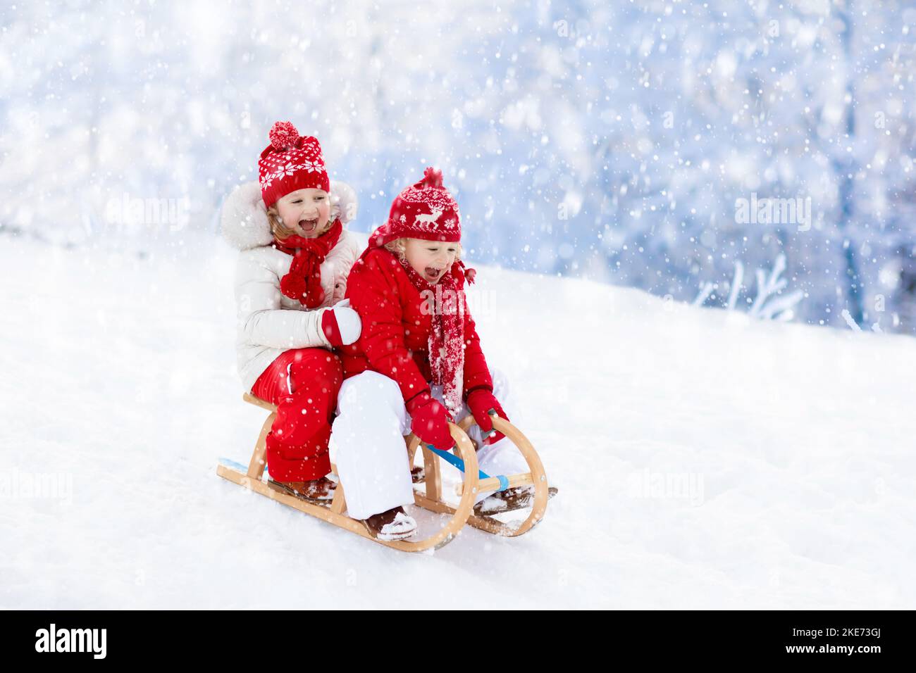 Little girl and boy enjoy a sleigh ride. Child sledding. Toddler kid ...