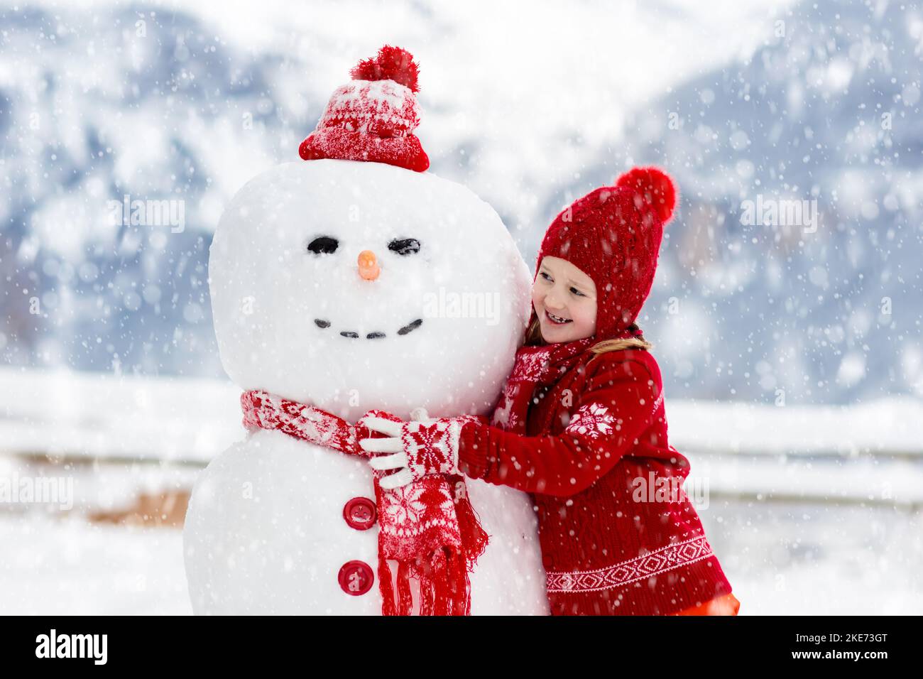 Child building snowman. Kids build snow man. Boy and girl playing ...