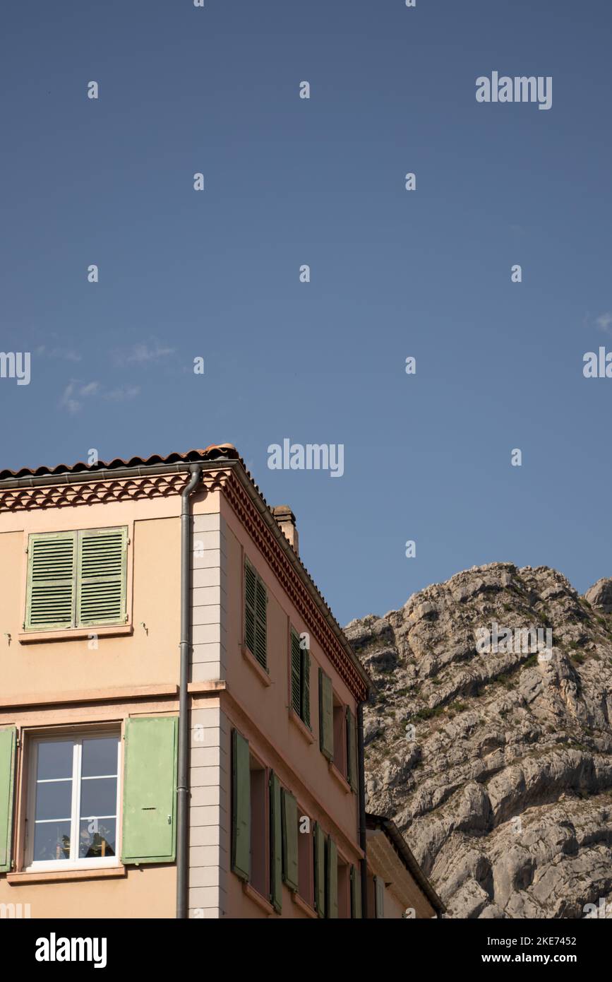 A low-angle vertical of a house near rocky cliff and clear,sunlit sky ...