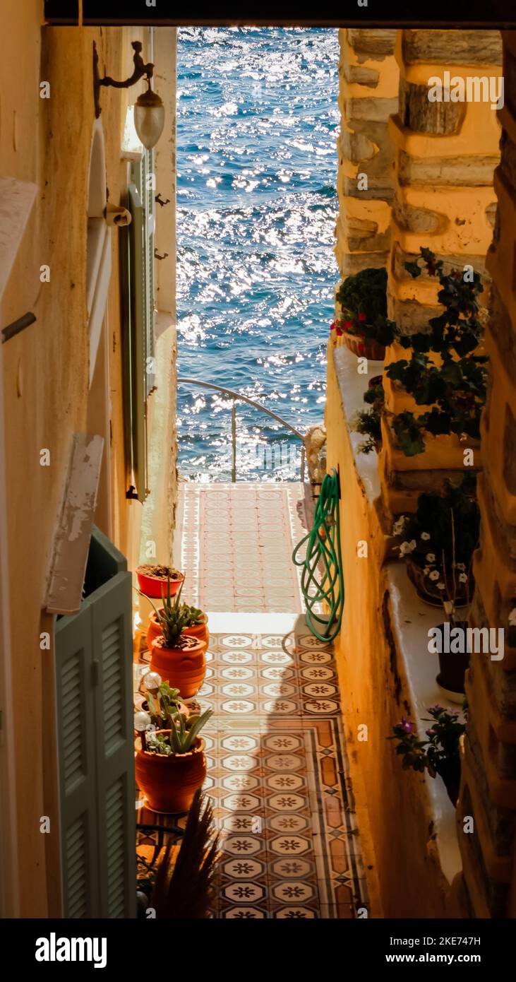 A vertical high-angle of a narrow corridor leading to the sunlit sea ...