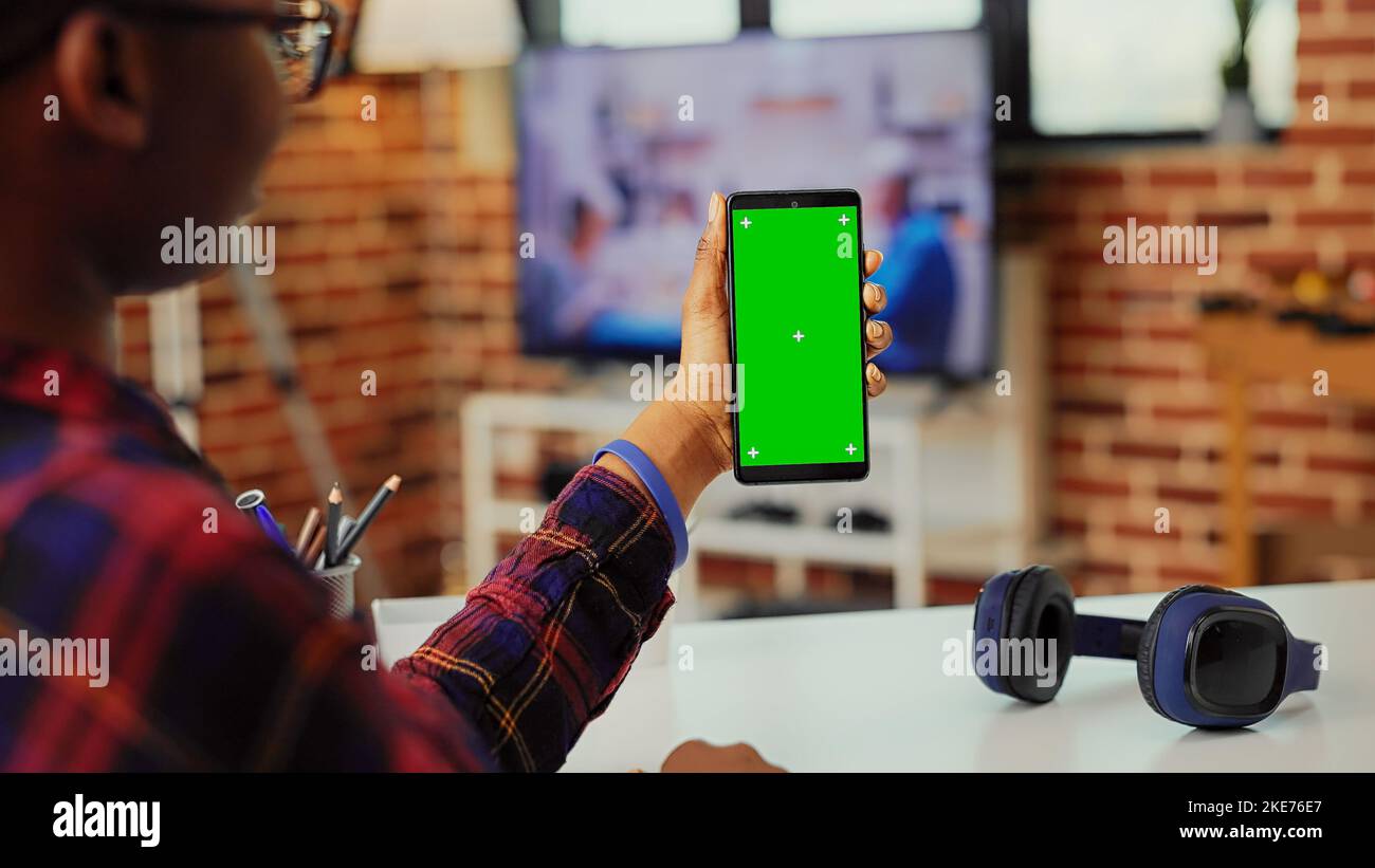 Young student looking at greenscreen display on mobile phone, analyzing ...