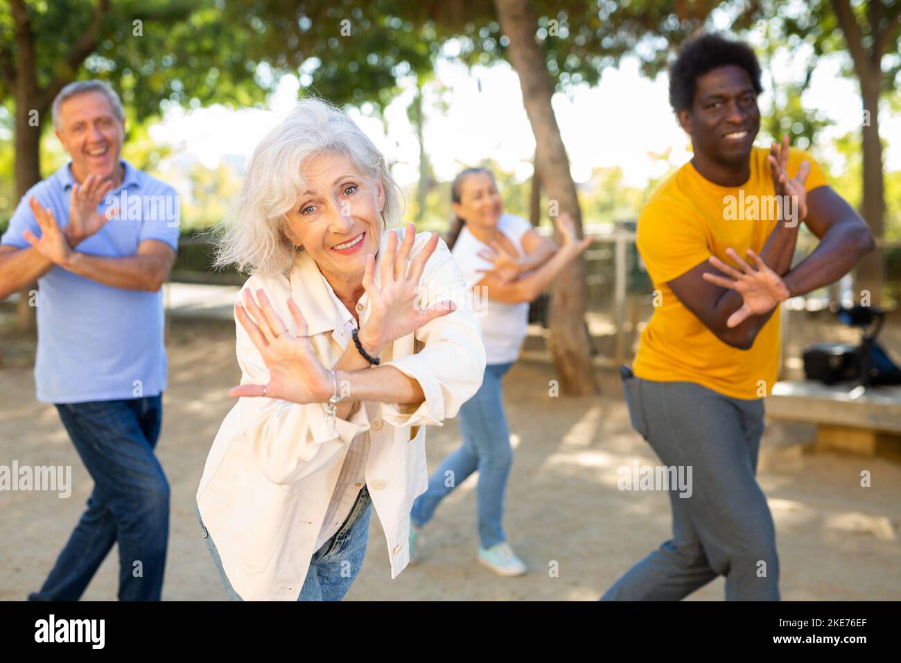Positive mature women and men practicing vigorous dance movements in ...