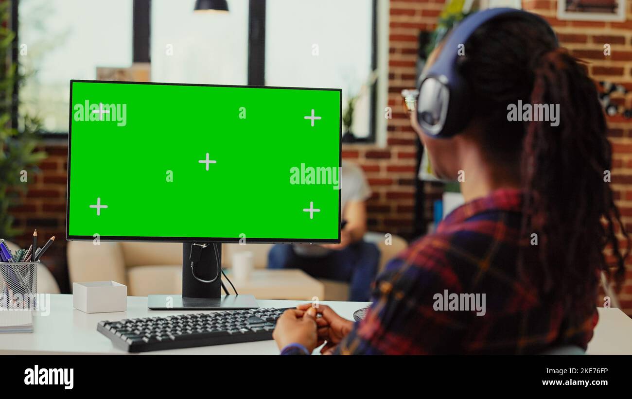 Female student with headset looking at greenscreen display, listening ...