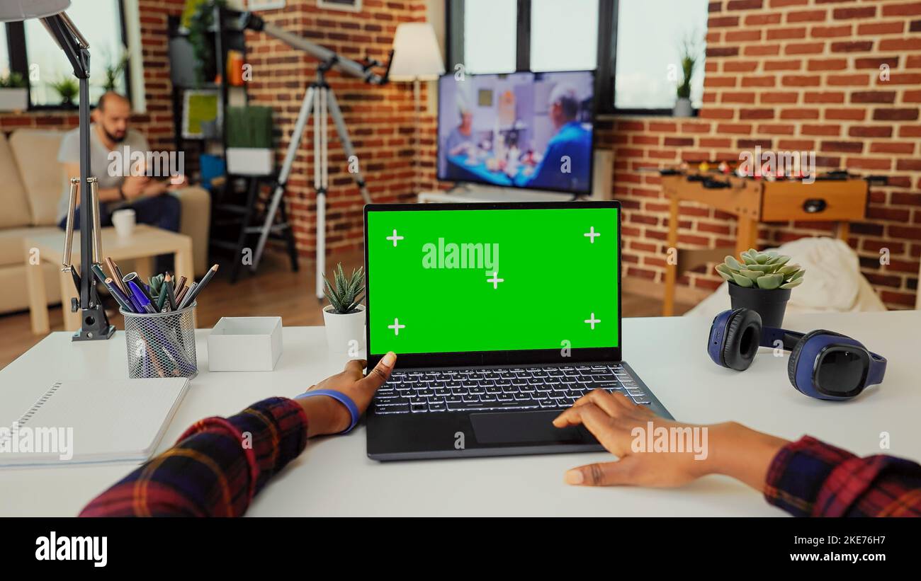 Young adult working on laptop with isolated green screen on display ...