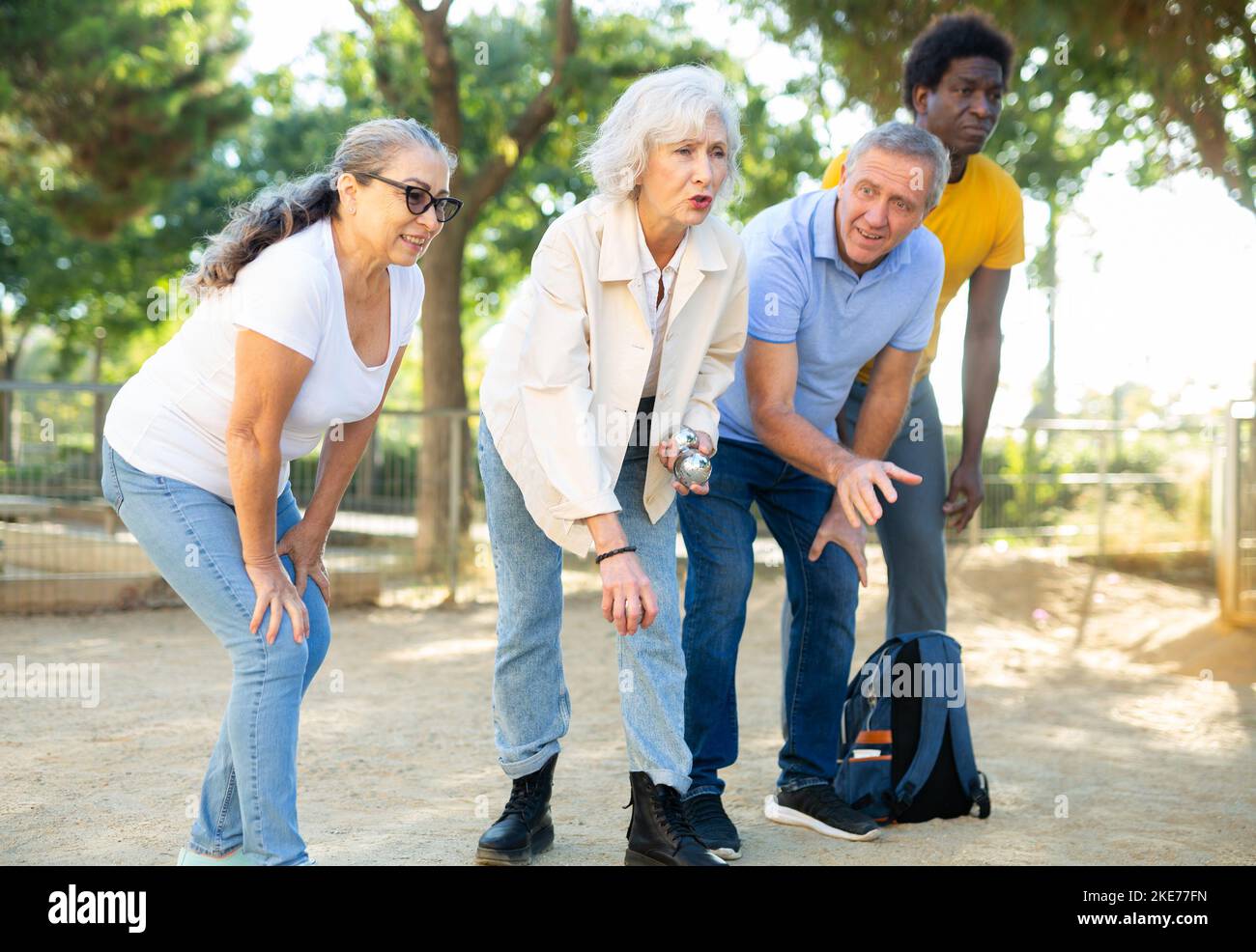 A group of multiracial mature adult people playing patanque game ...