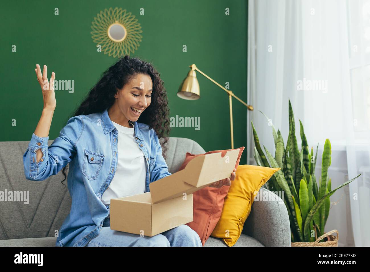 Young beautiful curly haired hispanic woman received package from ...