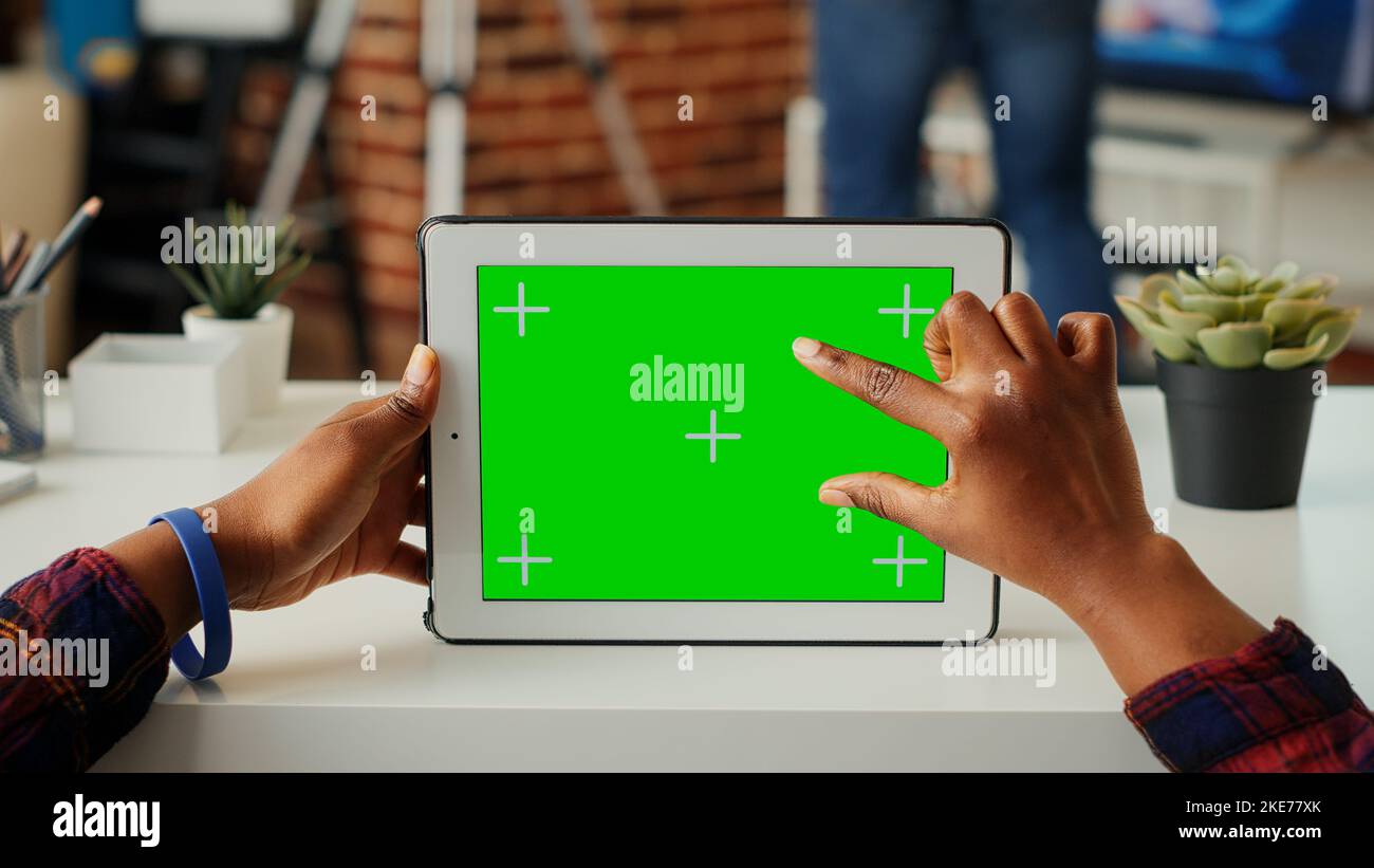 Young entrepreneur using horizontal greenscreen on wireless gadget at ...