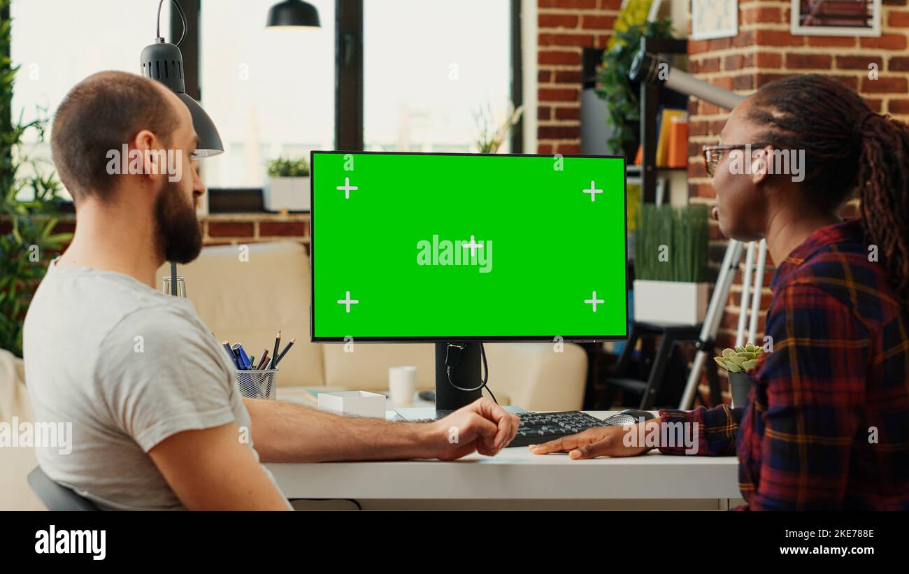 Diverse people working with greenscreen monitor on computer, analyzing isolated chroma key on ...