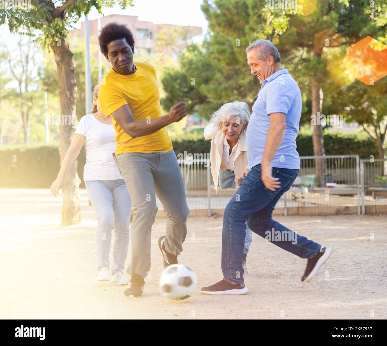 Happy mature people playing football in park Stock Photo - Alamy