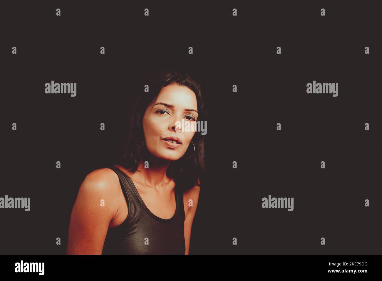 Studio portrait of young woman looking at camera against simple studio ...