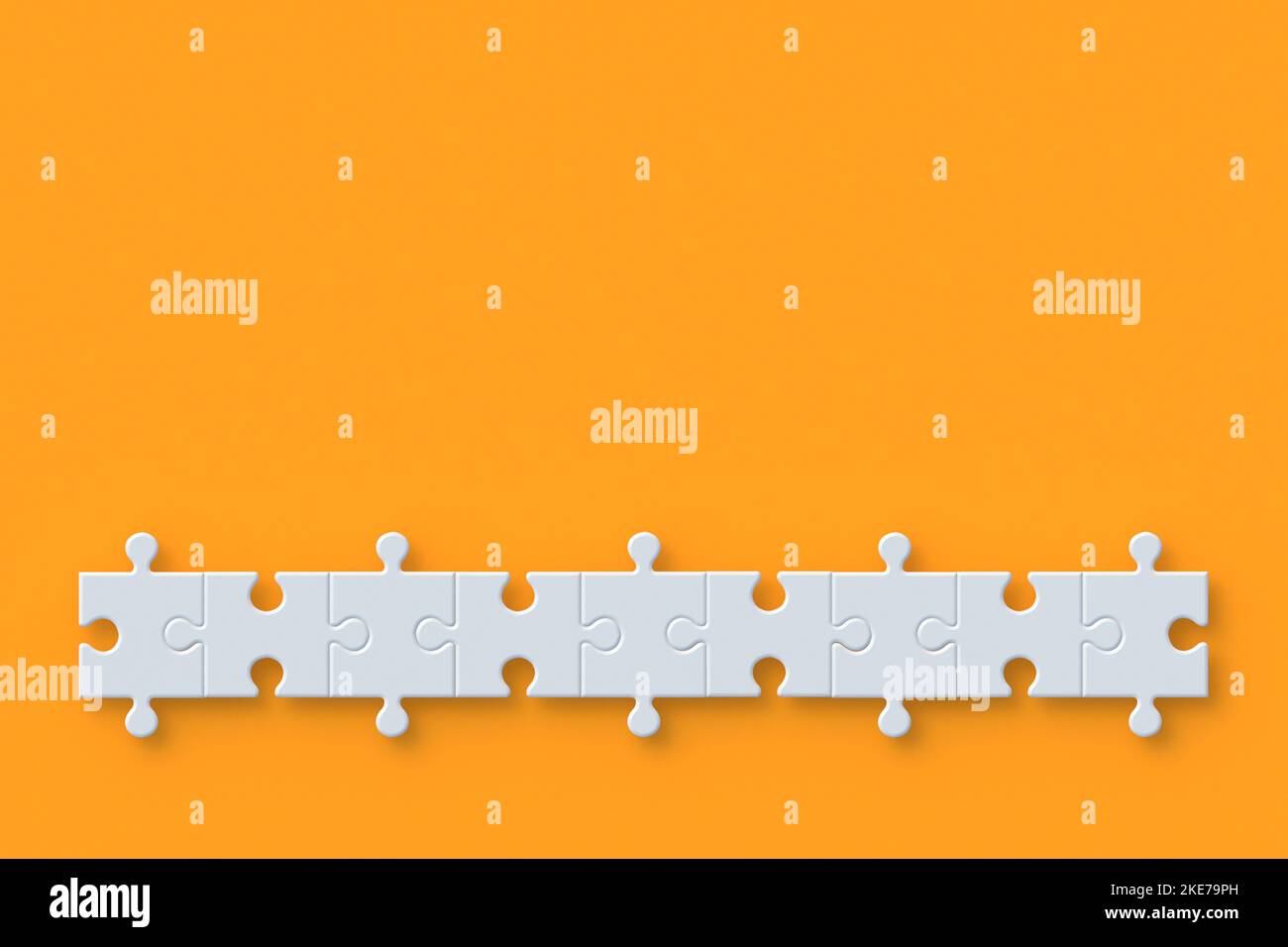 Row of unfinished jigsaw puzzle pieces on orange background. Copy space ...