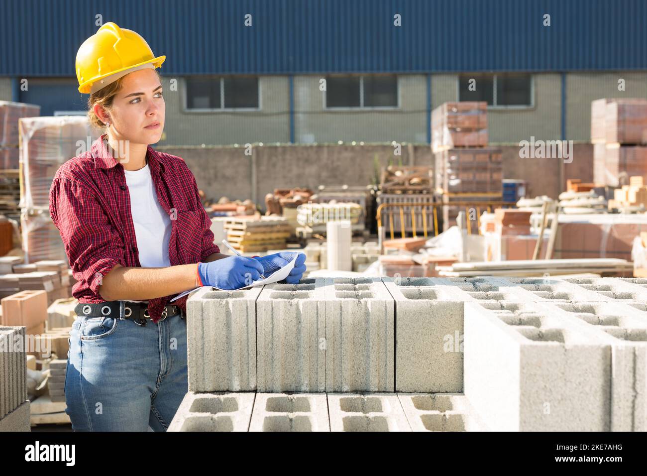 Young girl employee working in a warehouse keeps records of ...