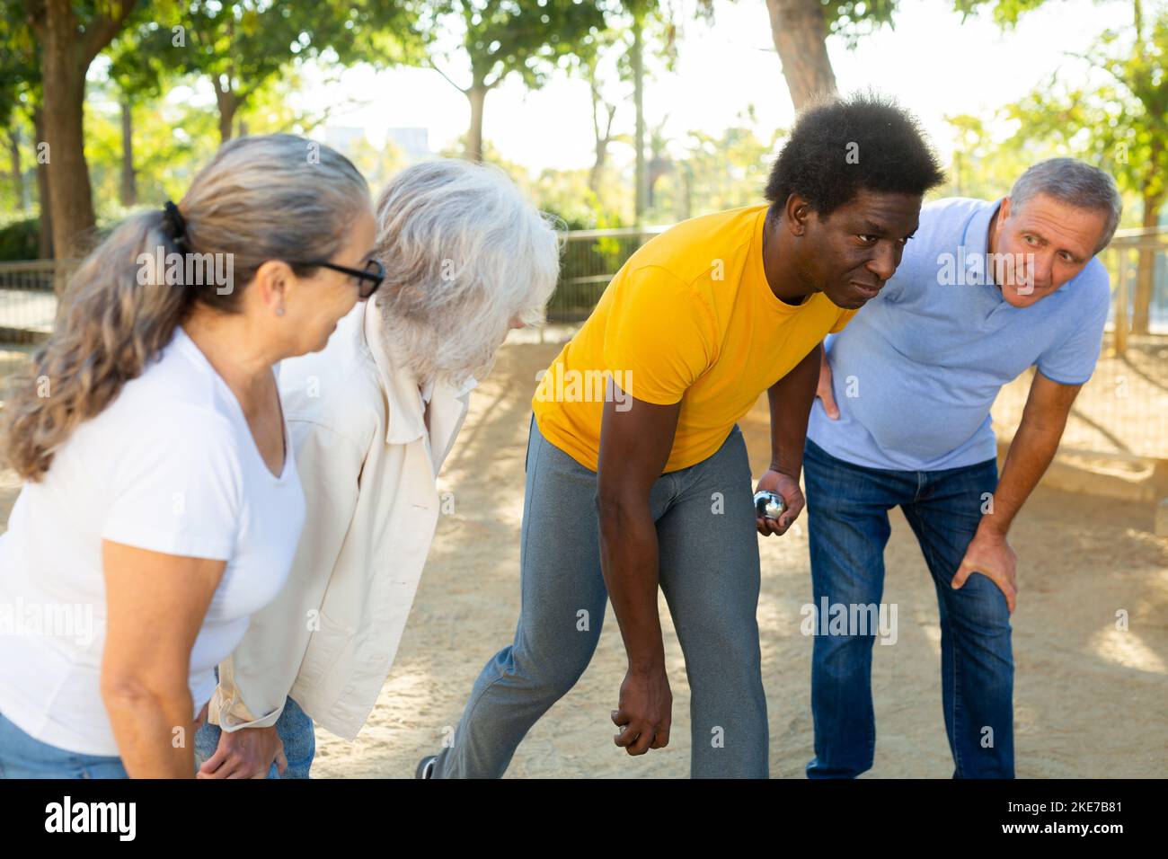 A group of multiracial mature adult people playing patanque game ...