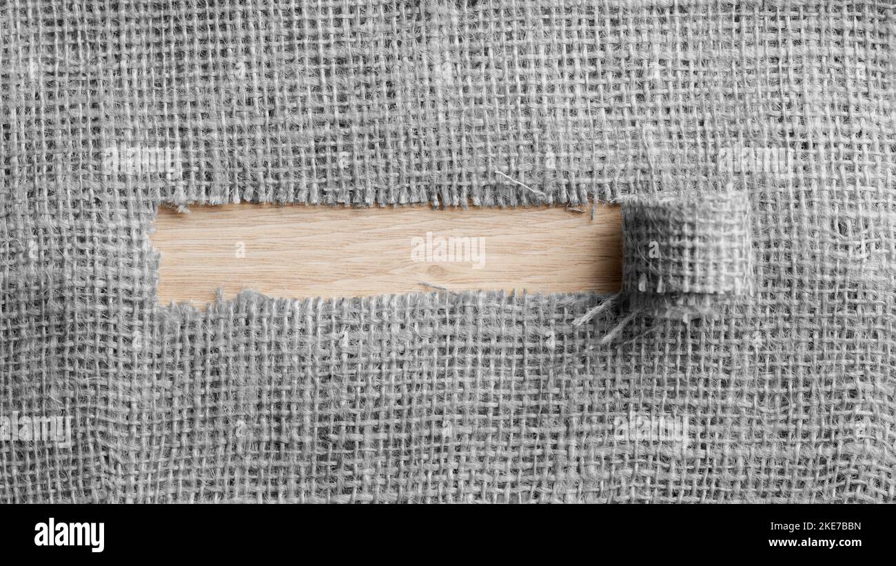 Top view of a rough linen fabric with a torn window in the middle with ...