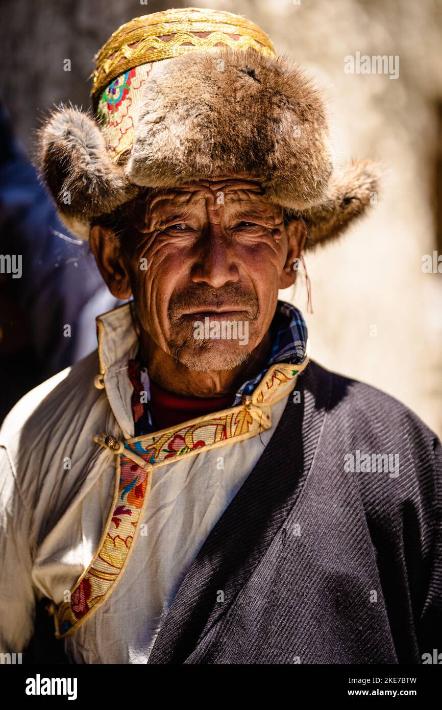 A vertical shot of an Old Tibetan Buddhist in traditional clothing at ...