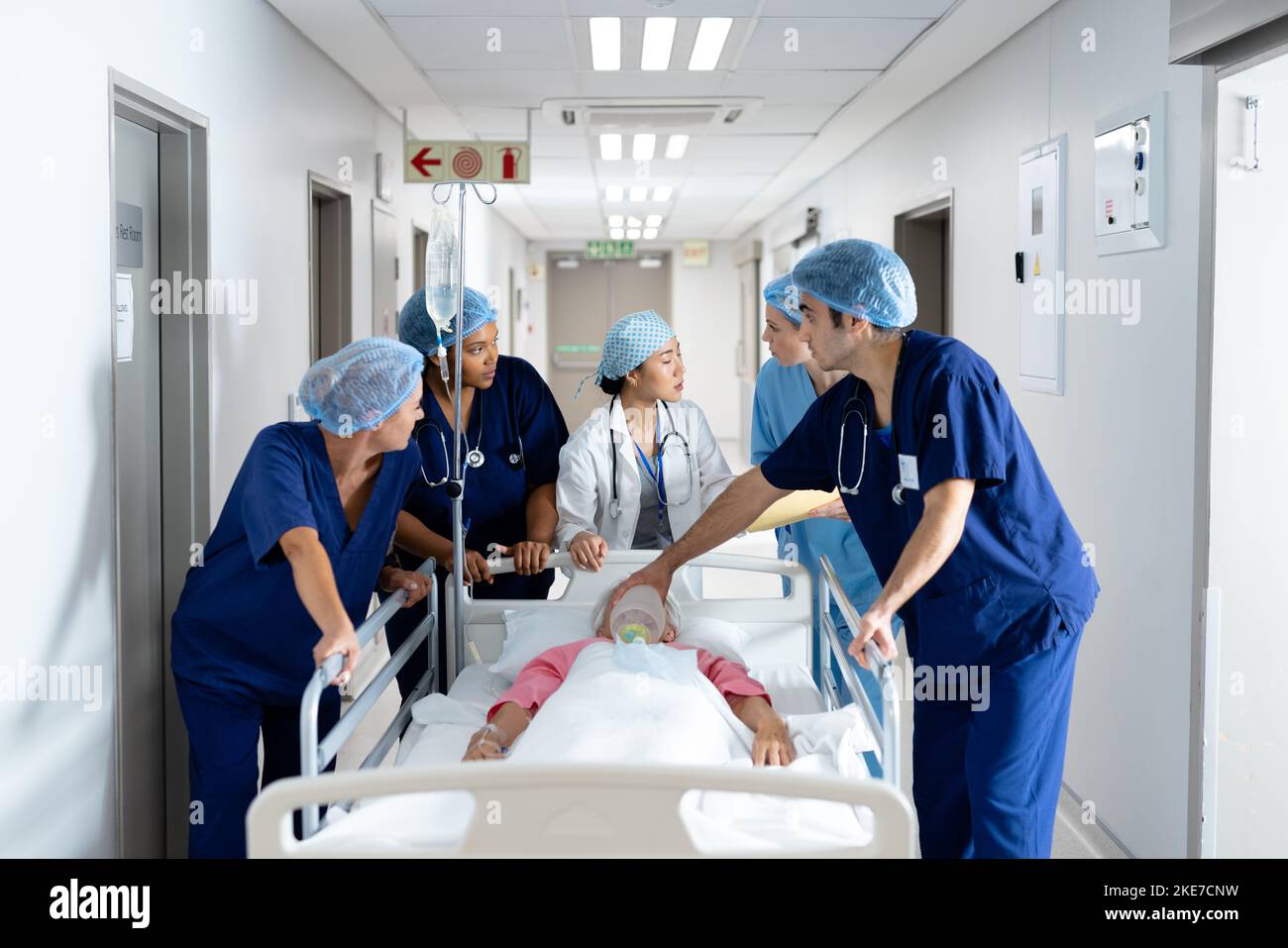 Diverse group of healthcare workers pushing patient in bed down ...