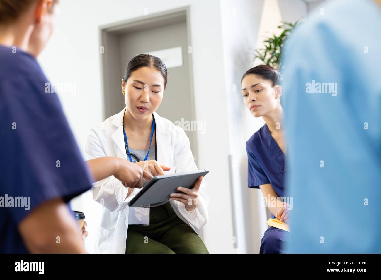 Asian female doctor with tablet sitting in discussion with diverse ...